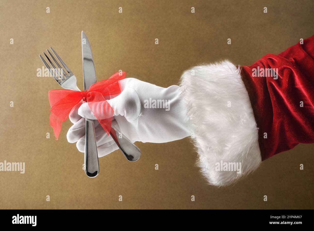 Santa Claus hand in suit and gloves holding cutlery with red bow ...