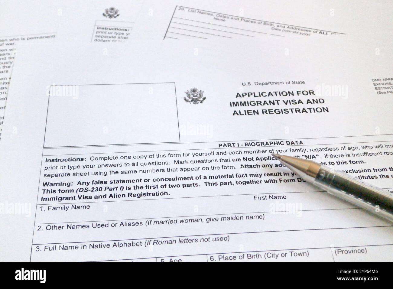 a ballpoint pen on the top of an application form for immigrant visa ...