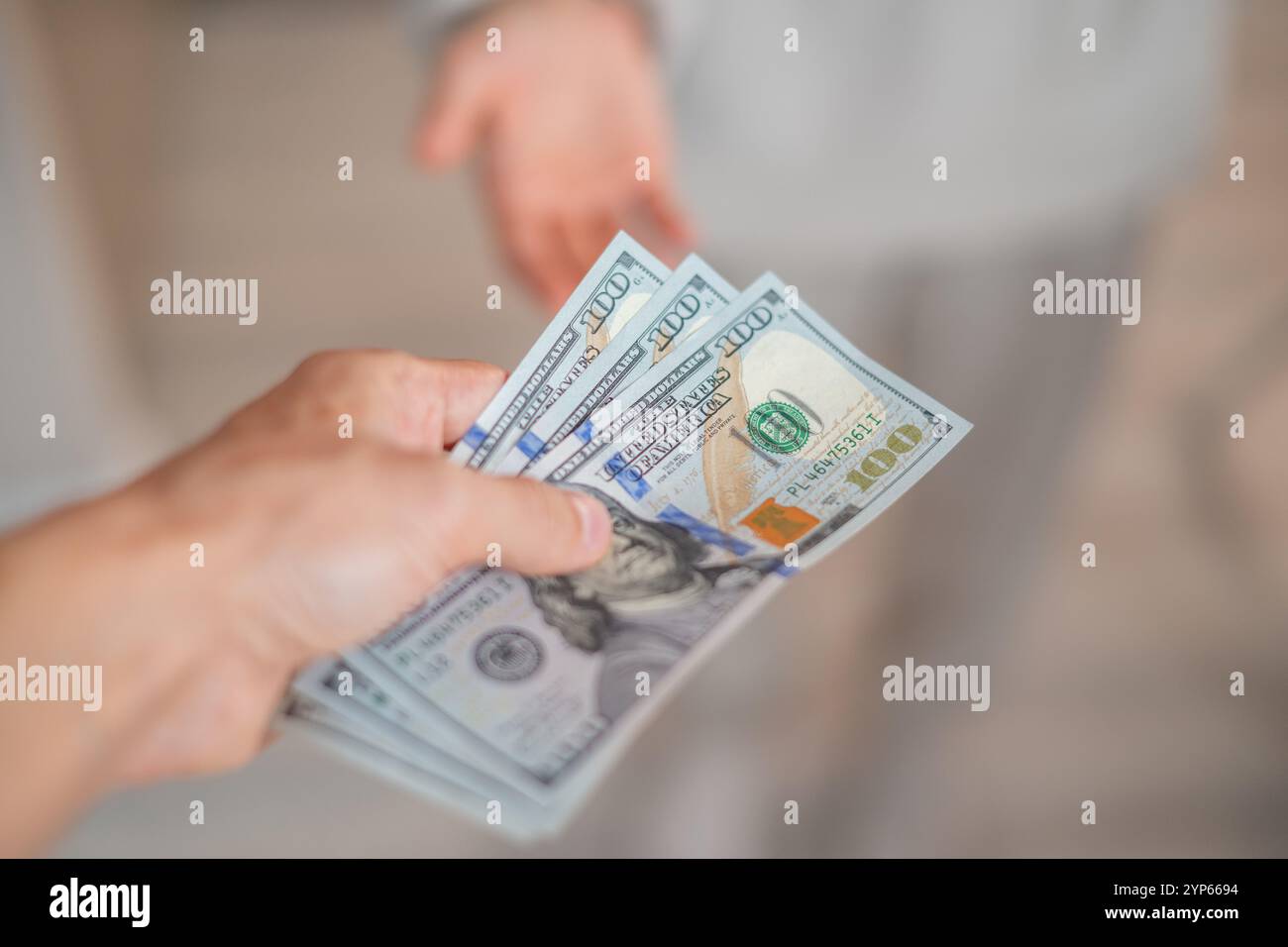 A hand passes hundred dollar bills to another person Stock Photo - Alamy