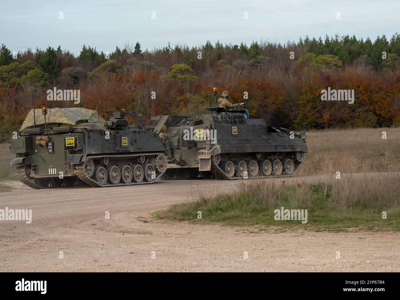 British army Warrior FV512 towing a Bulldog FV434 along a dirt track ...