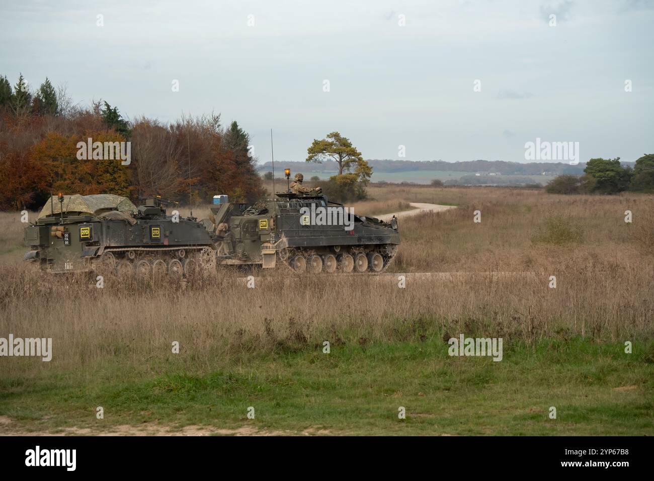 British army Warrior FV512 towing a Bulldog FV434 along a dirt track ...