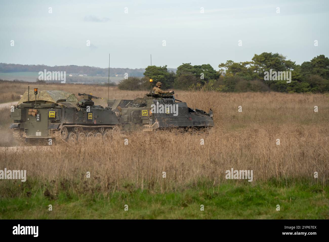British army Warrior FV512 towing a Bulldog FV434 along a dirt track ...