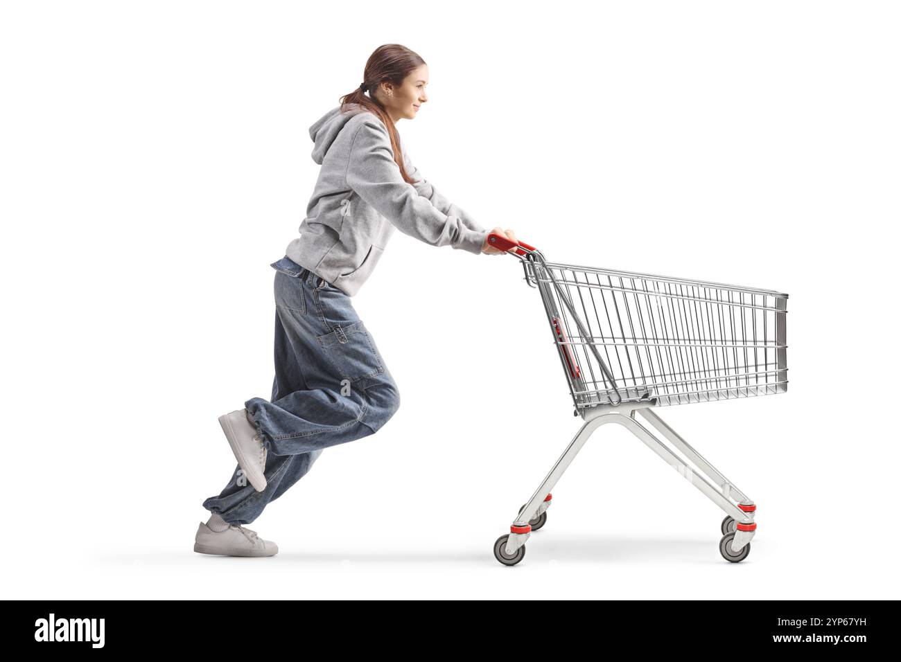 Teenage girl running with a shopping cart isolated on white background ...