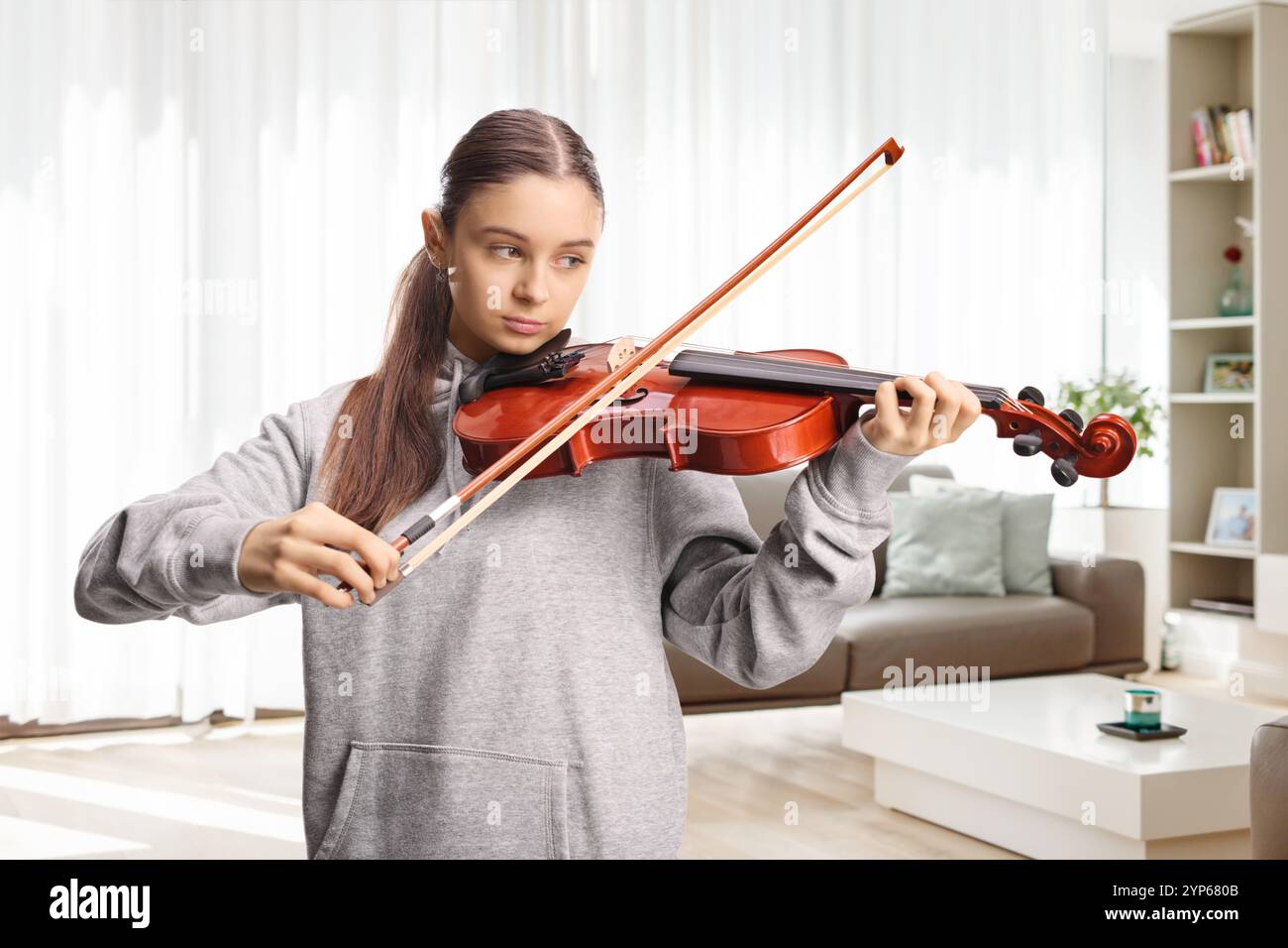 Teenage girl practicing violin at home in a living room Stock Photo - Alamy