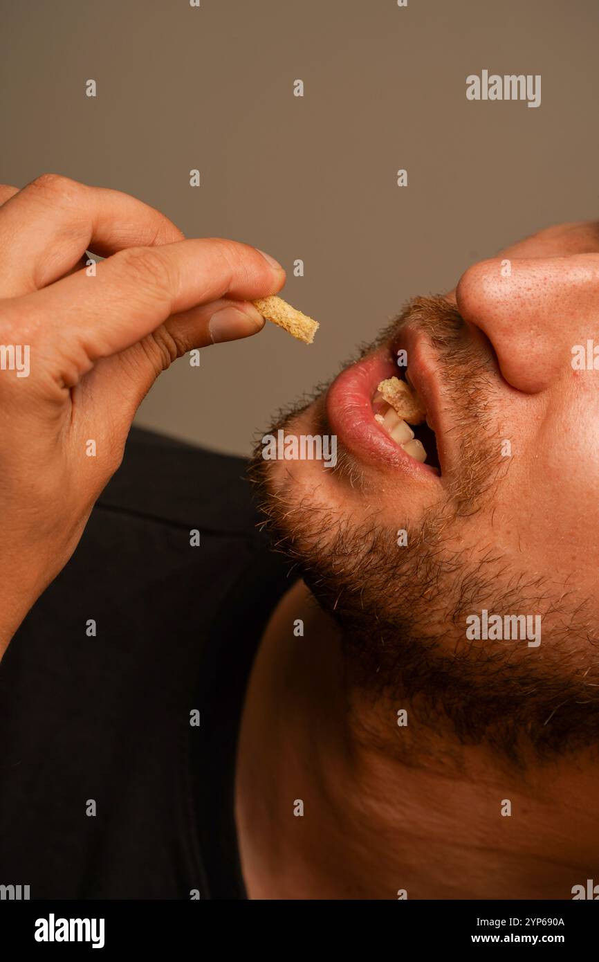 A close-up of a man about to eat a crunchy snack in the form of a ...