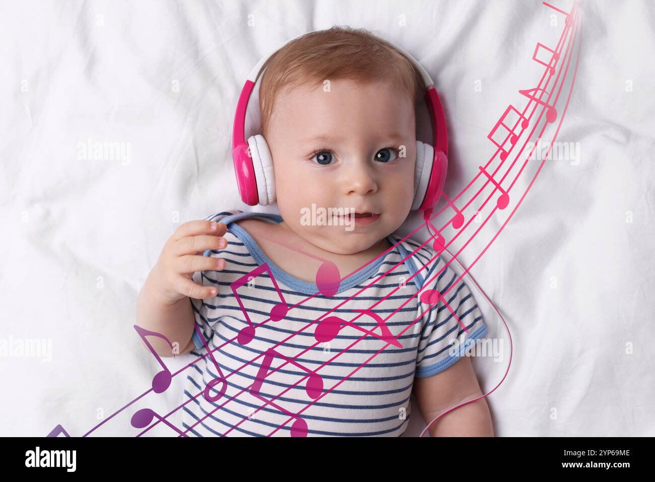 Cute little baby with headphones lying on bed, top view. Music notes ...