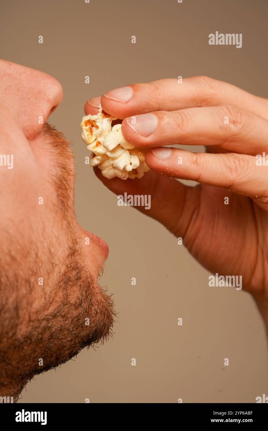 A close-up of a person eating popcorn with their hands, pouring it into ...