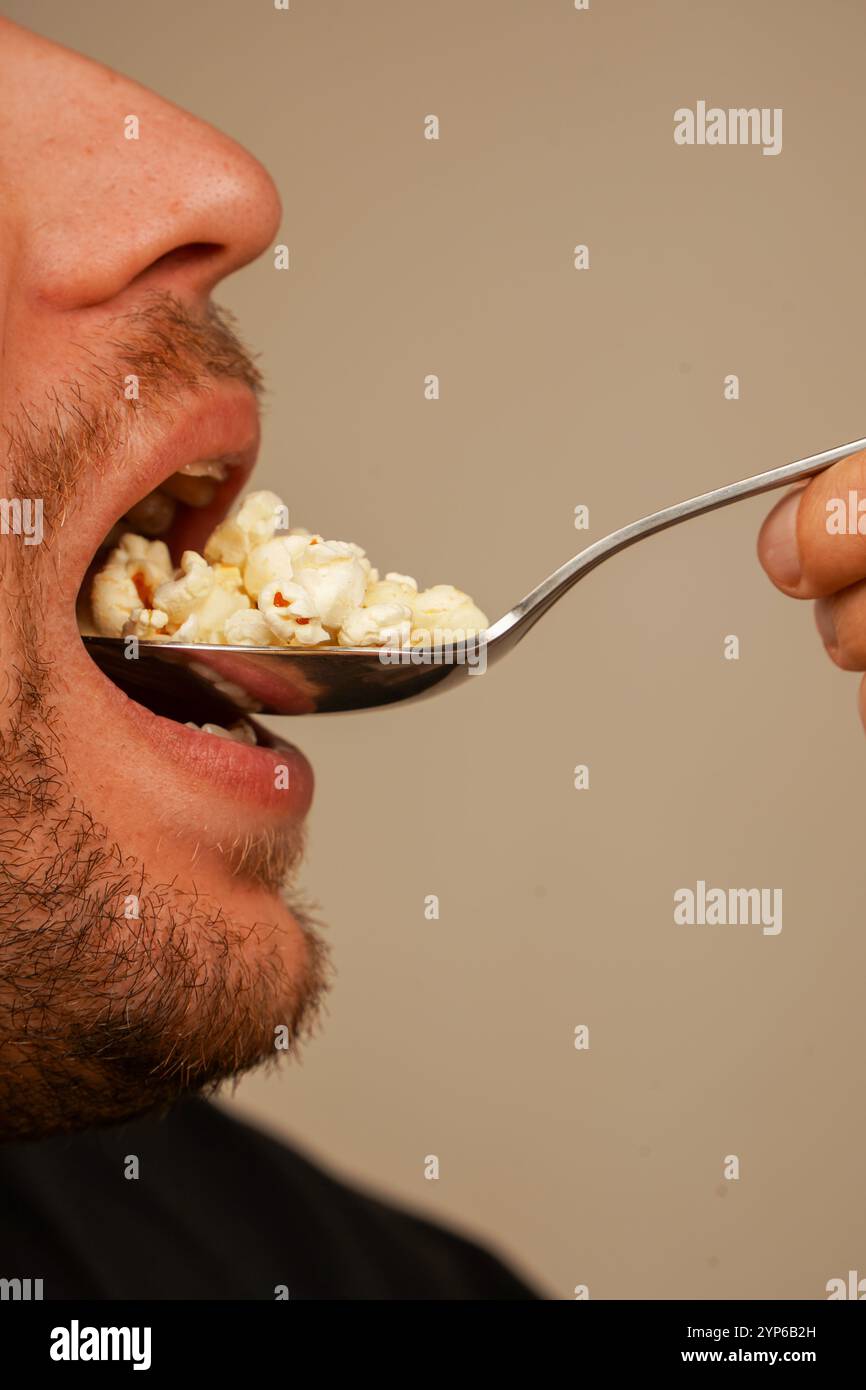 A macro shot of popcorn in a spoon as a man eats it. The texture of the ...