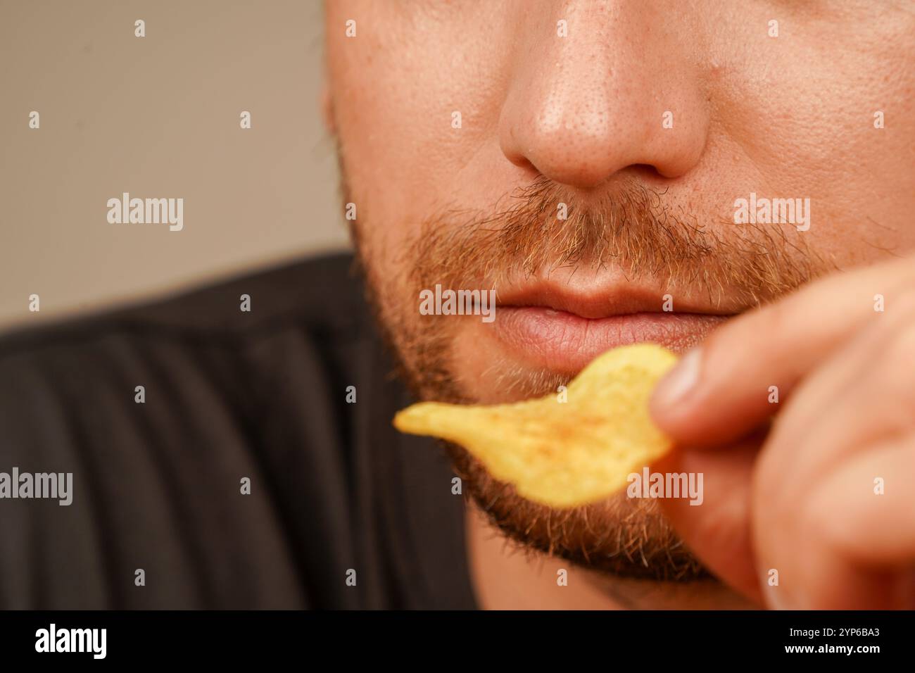 Bearded man holding potato chips in front of him. Focused shot of a man ...