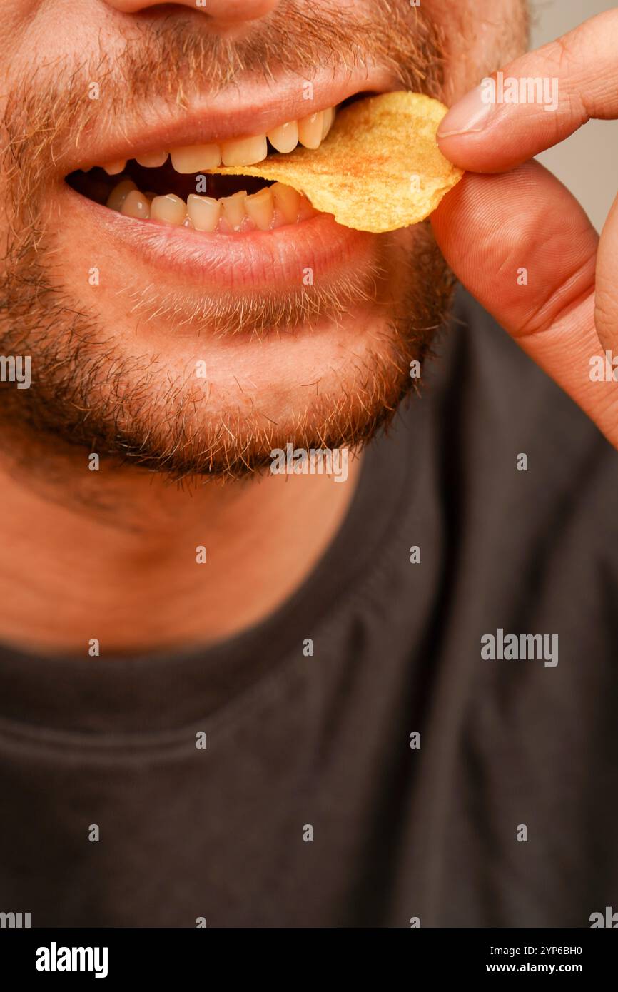 Crispy potato chips being bitten by a man in a casual setting. Perfect ...
