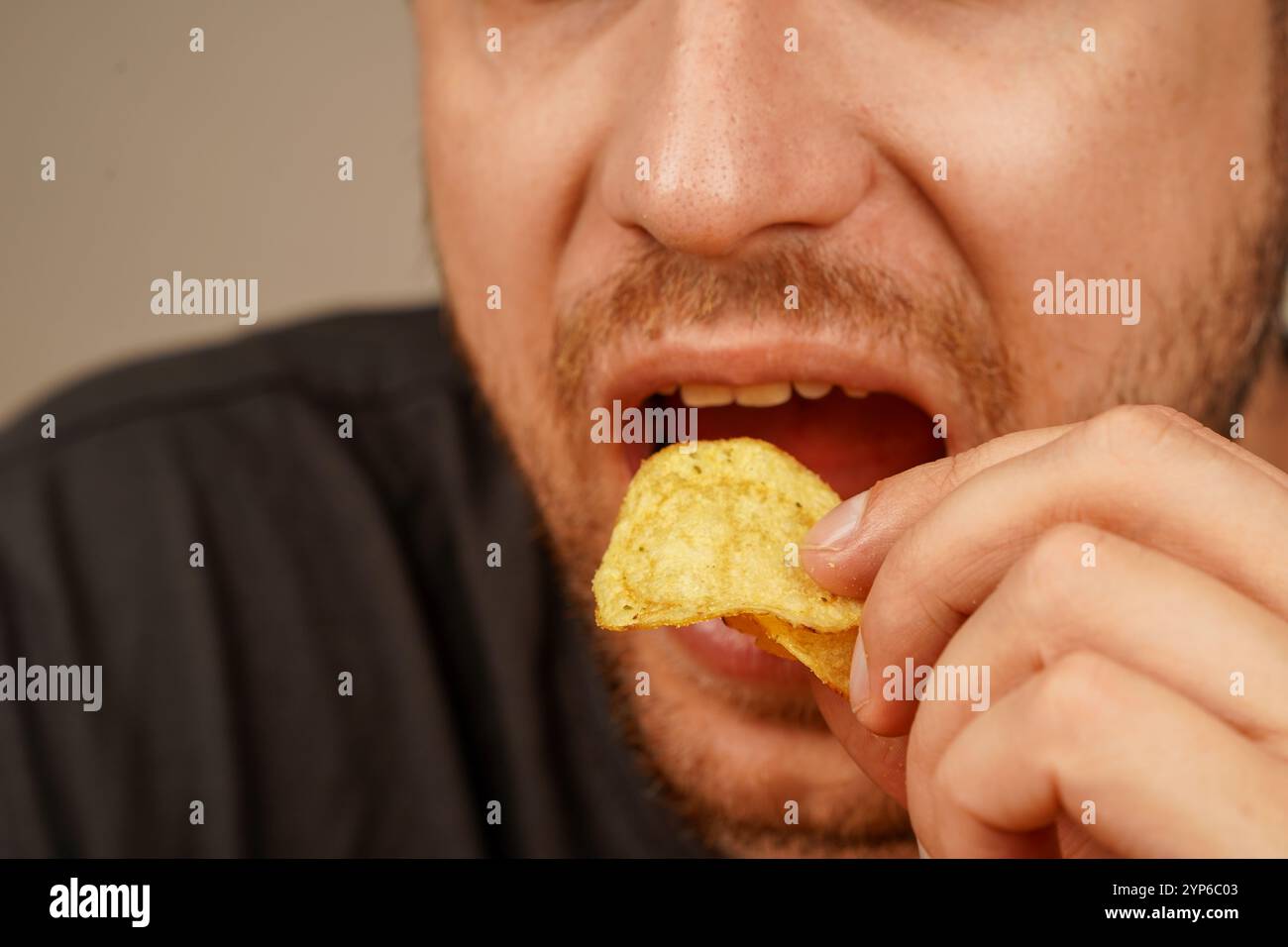 Bearded man bites golden potato chips. Perfect for food and lifestyle ...