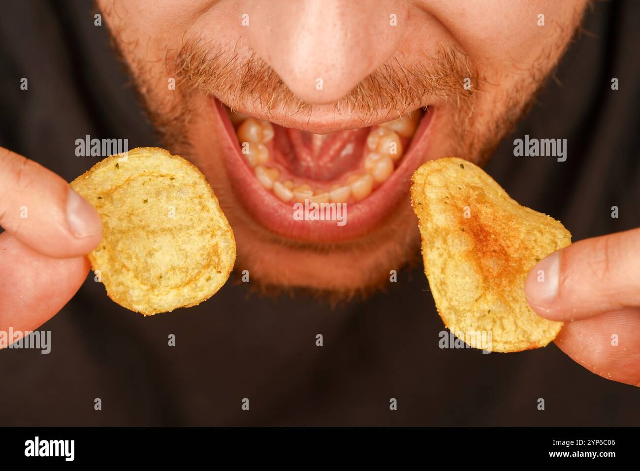 Bearded man bites golden potato chips. Perfect for food and lifestyle ...