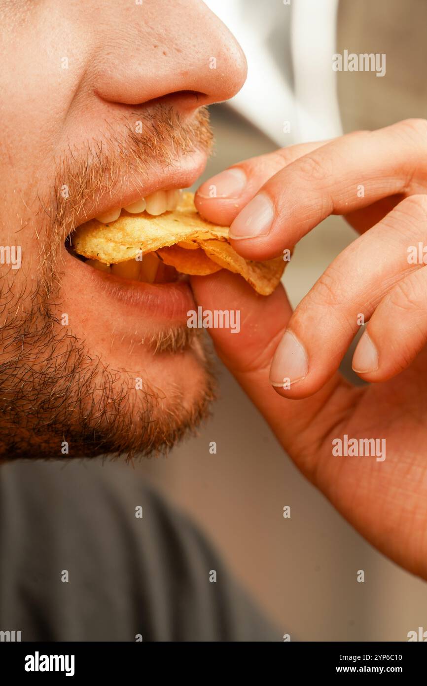 Bearded man bites golden potato chips. Perfect for food and lifestyle ...