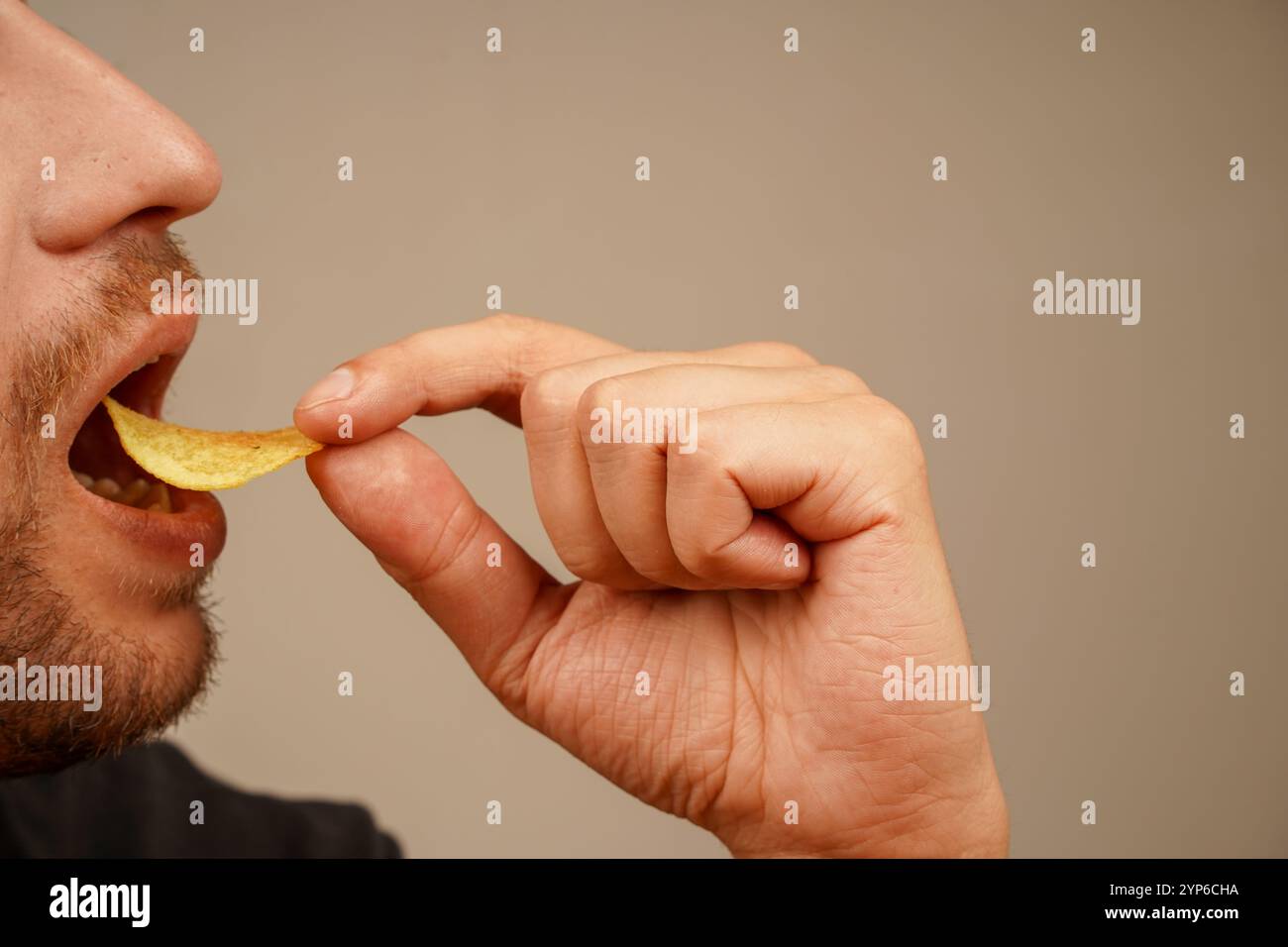 A close-up of a man trying to take a bite of chips. Great for depicting ...
