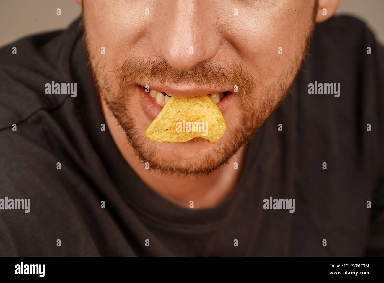 Close-up of a man enjoying crispy potato chips. Perfect for snacking ...