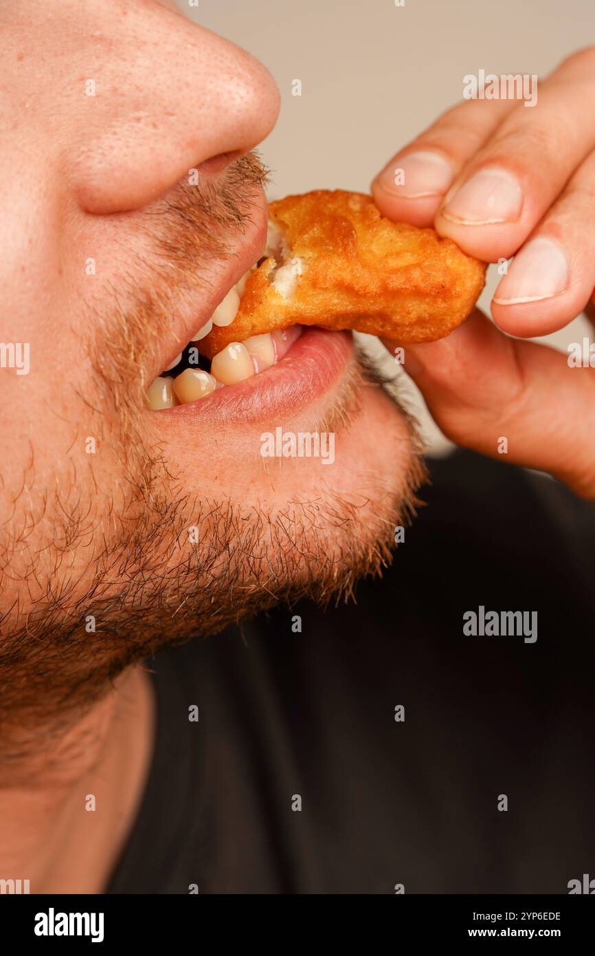 Man enjoying a nugget with rich details of crispy texture and golden ...