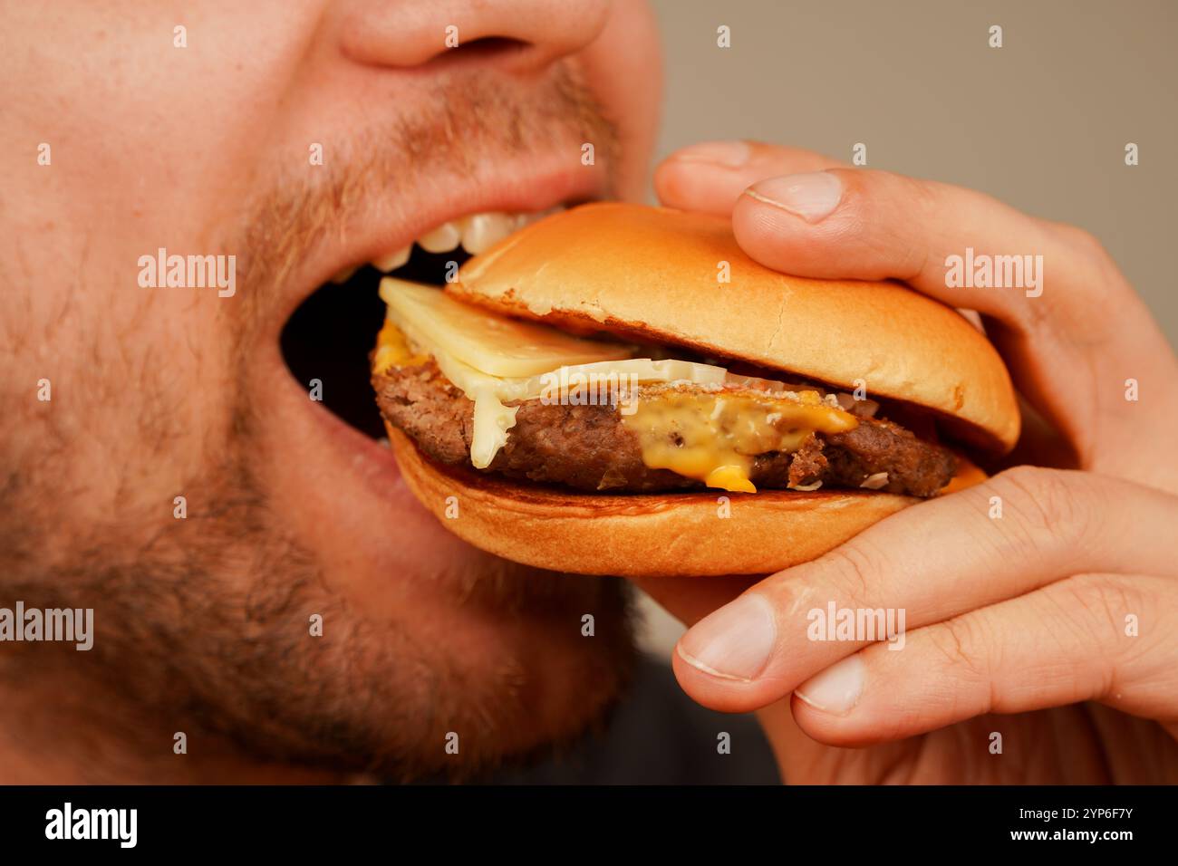Man eating a classic burger with melted cheese. Perfect for ...