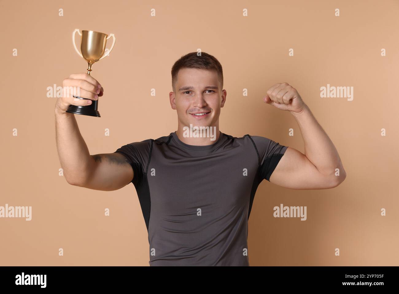 Happy winner with golden trophy cup on beige background Stock Photo - Alamy