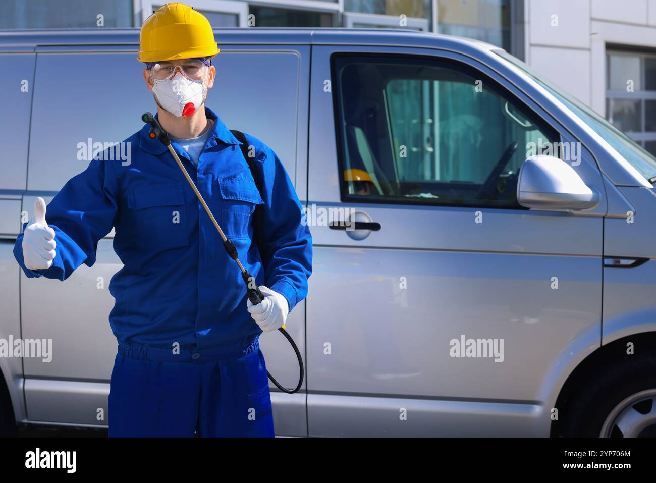 Pest control worker with spray tank showing thumbs up outdoors Stock ...