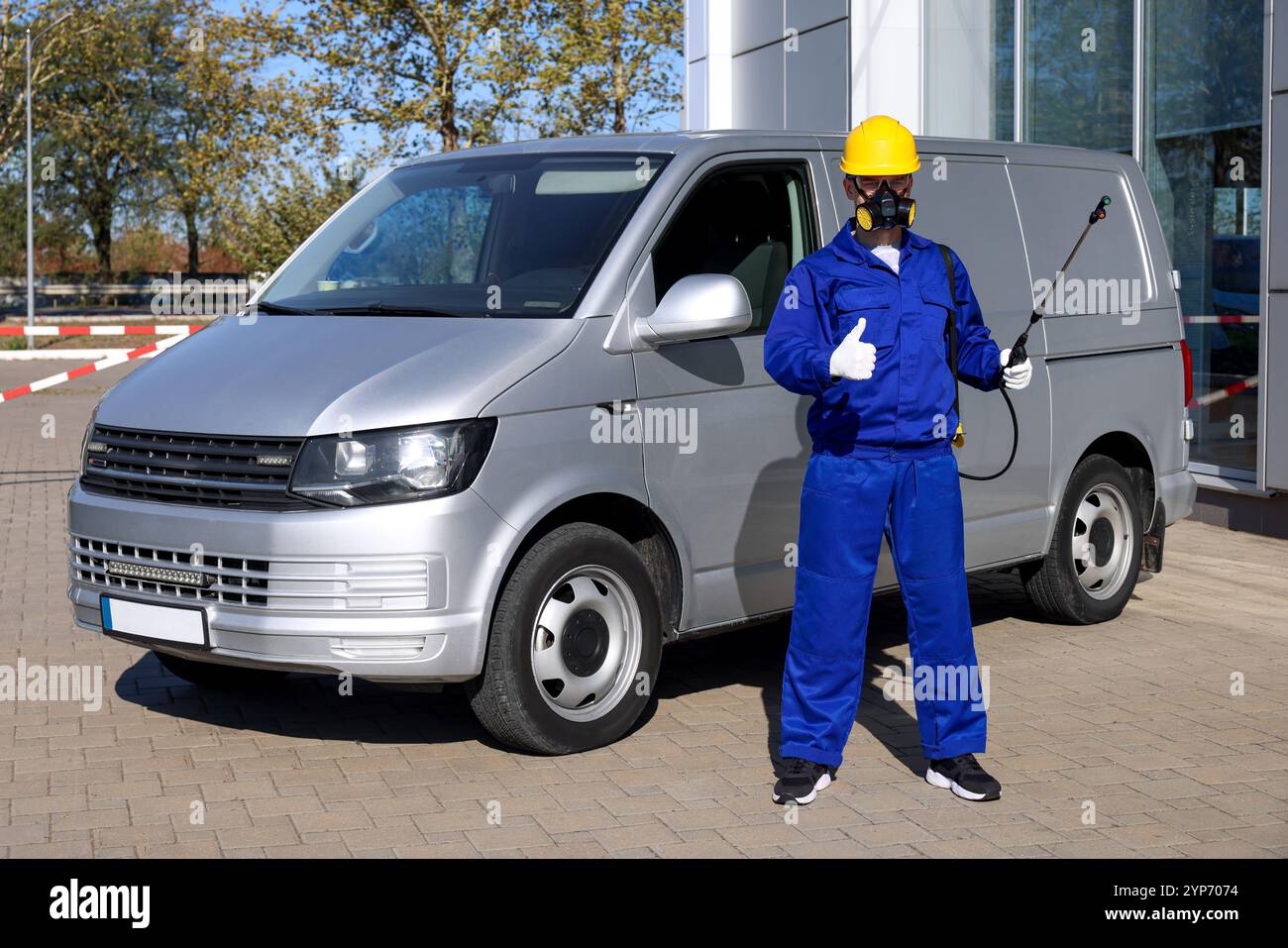 Pest control worker with spray tank showing thumbs up outdoors Stock ...
