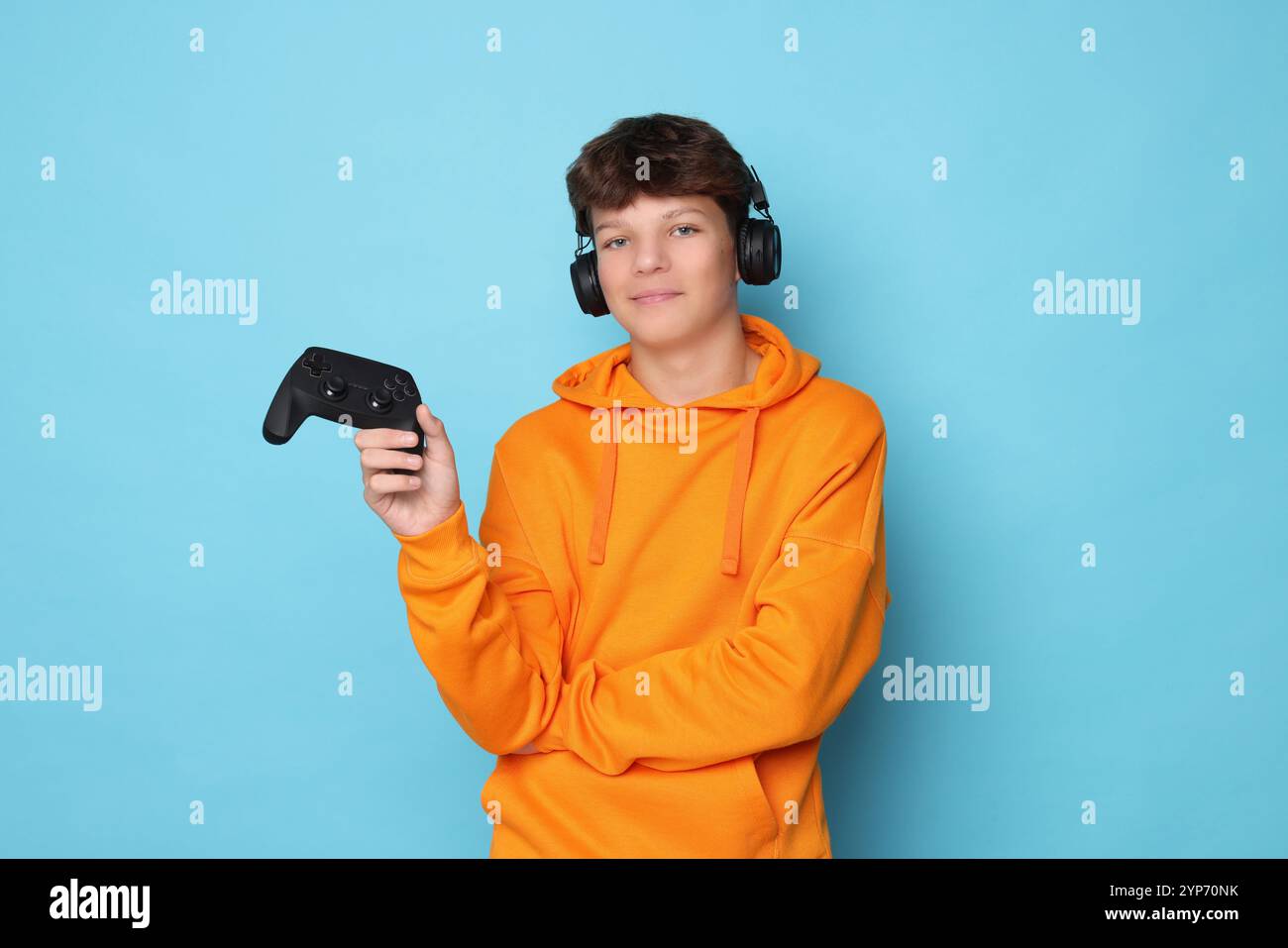 Teenage boy with controller on light blue background Stock Photo - Alamy