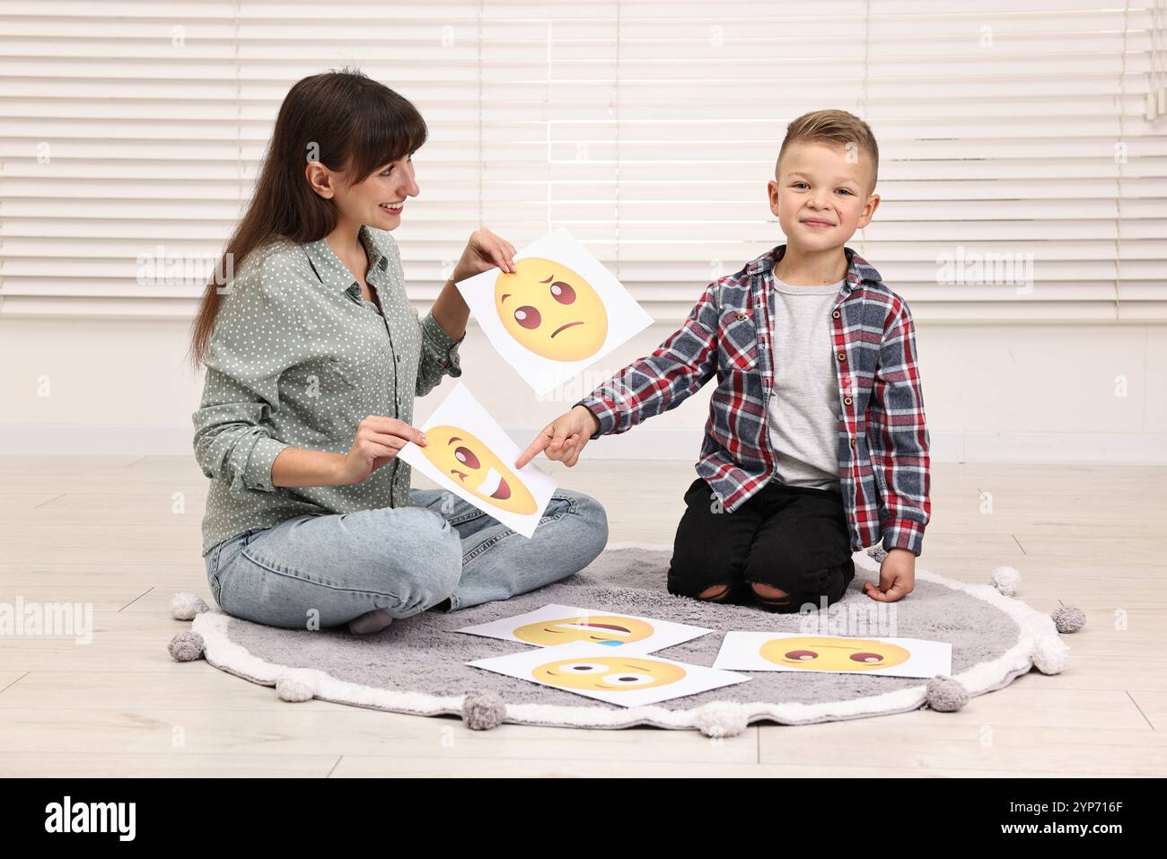 Autism therapy. Little boy choosing emoticon with smiling psychologist ...