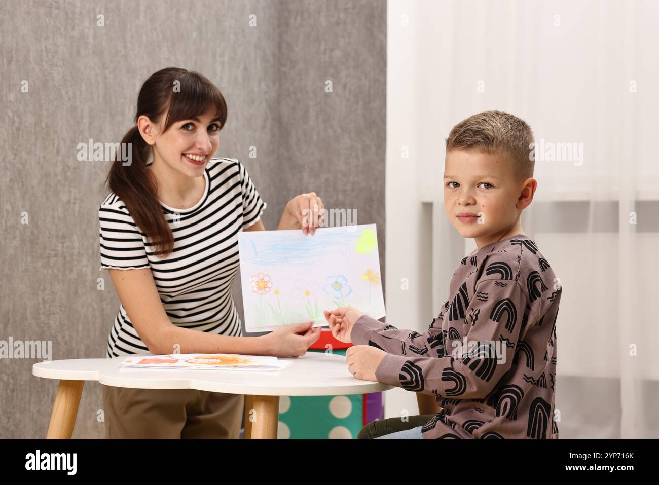 Autism therapy. Smiling psychologist working with little boy at table ...
