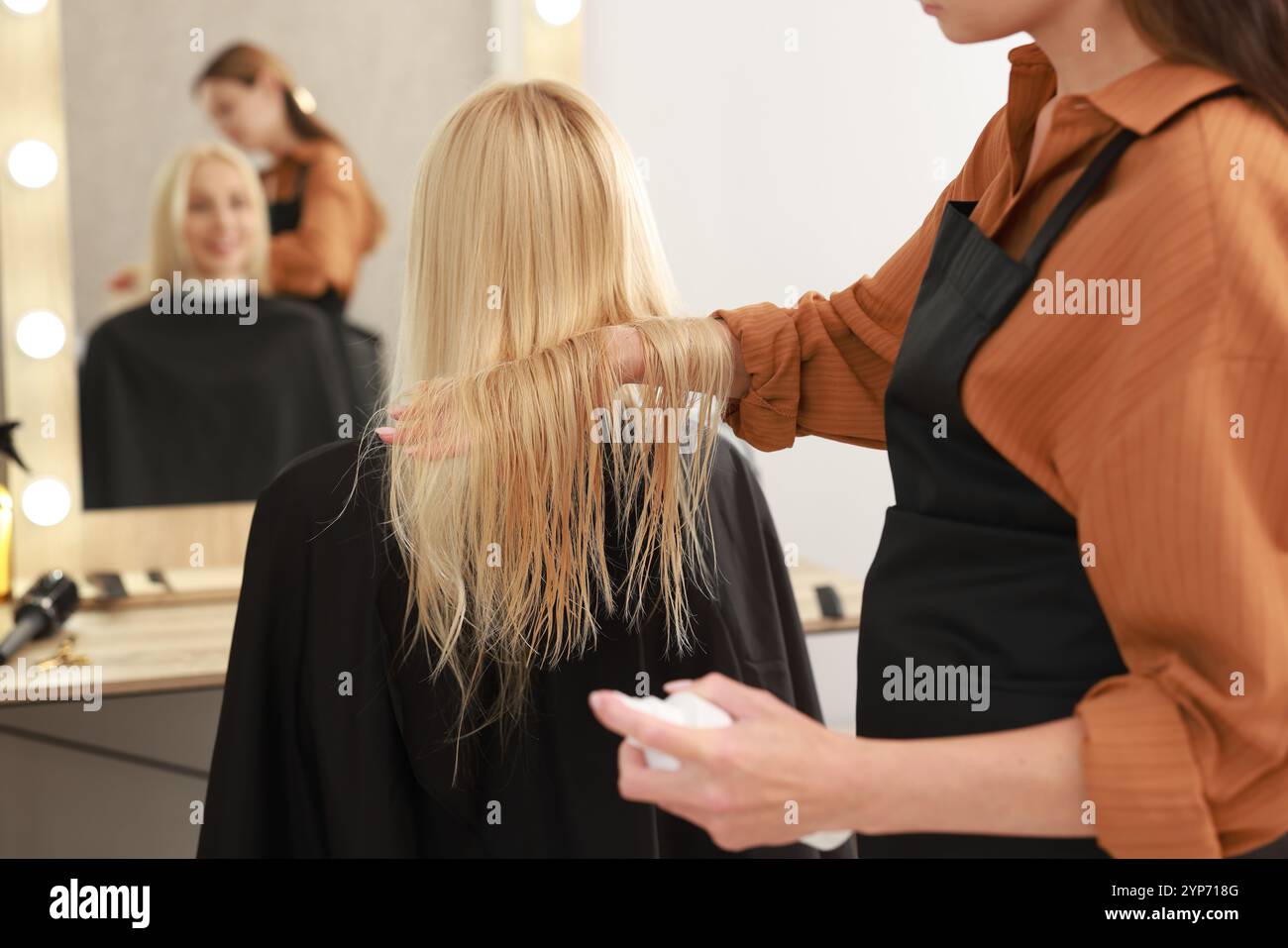 Hairdresser using spray while making stylish haircut in salon Stock ...