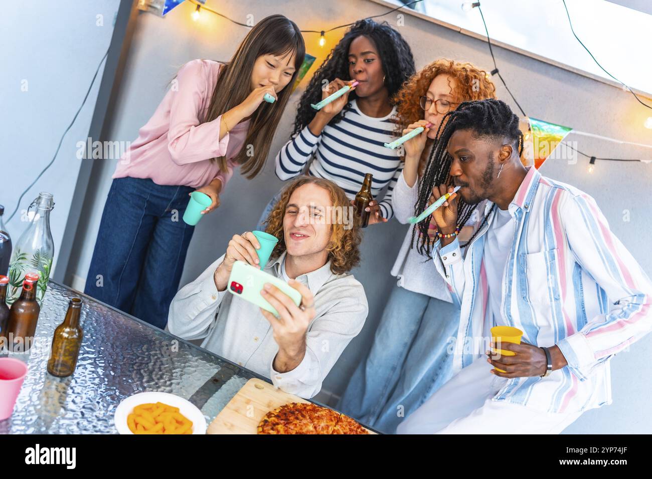 Happy caucasian man taking selfie while friends blowing streamers ...