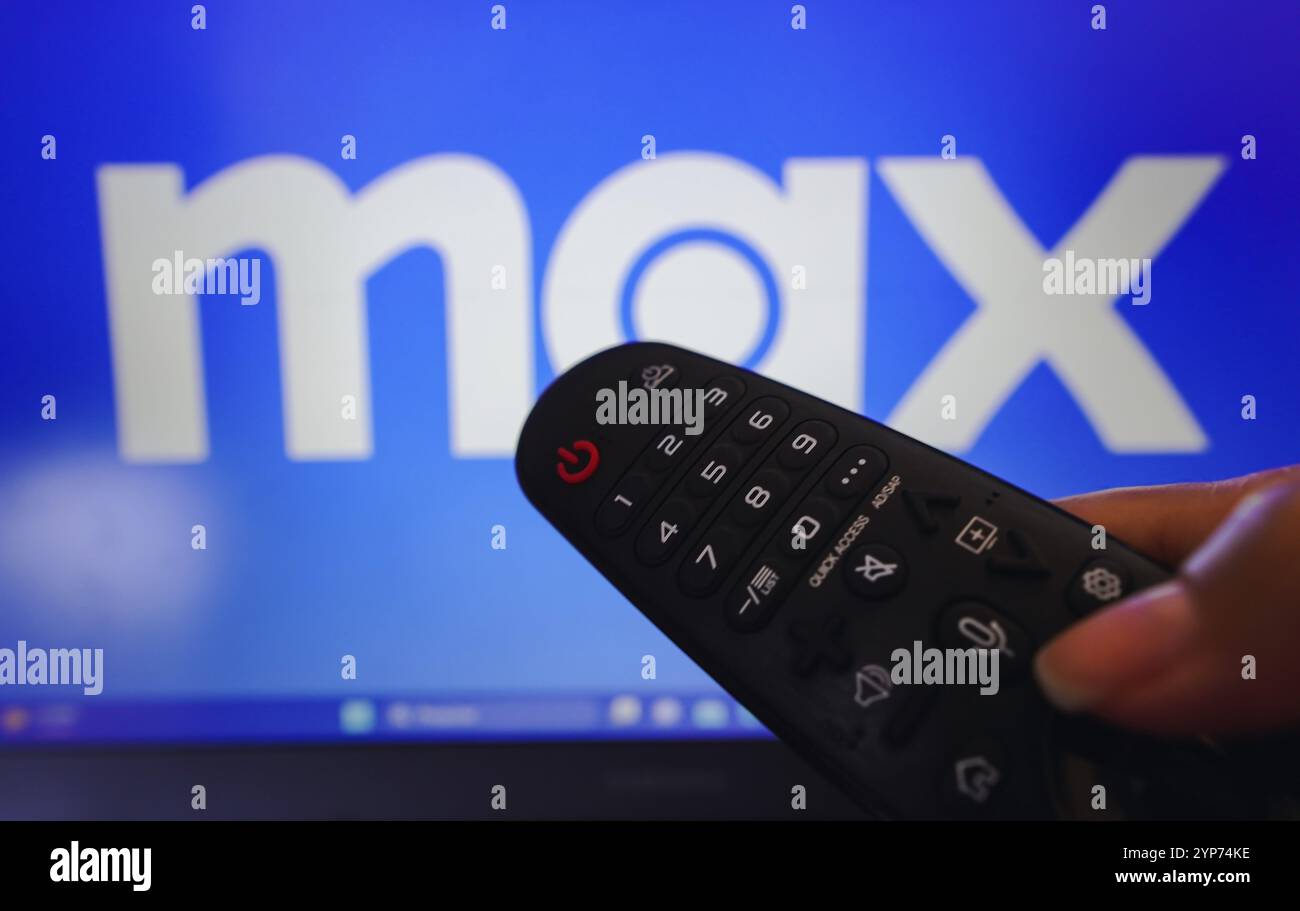 In this photo illustration, a hand holding a TV remote control in front ...