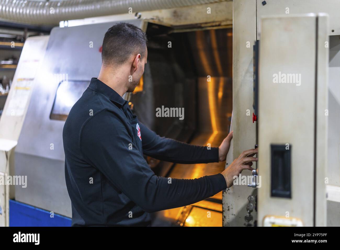 Rear view of a male operator working using lather cnc machine in the ...