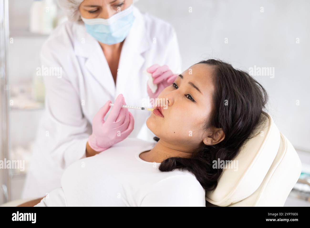 Middle-aged doctor giving injection in face Stock Photo - Alamy
