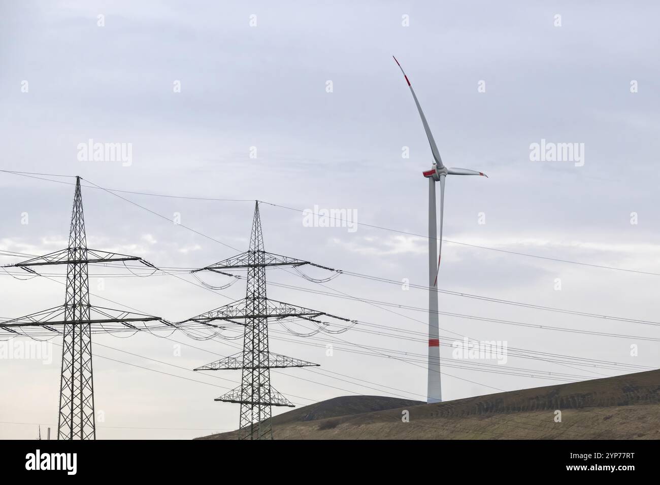High-voltage pylons with wind turbine in german industrial landscape ...