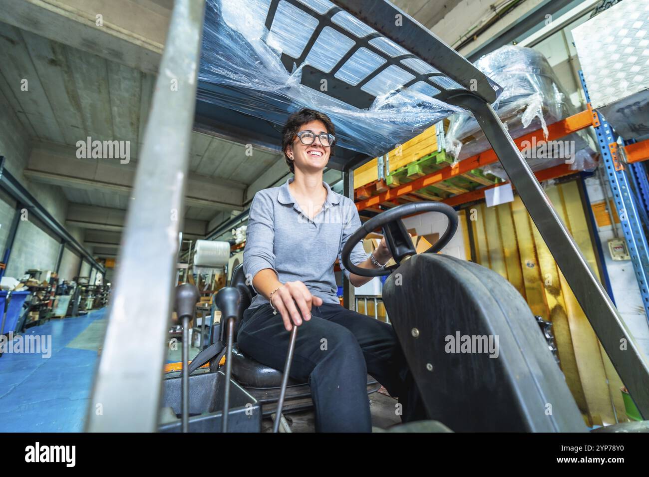 Happy female manual worker using forklift in a warehouse of a cnc metallurgic factory Stock ...