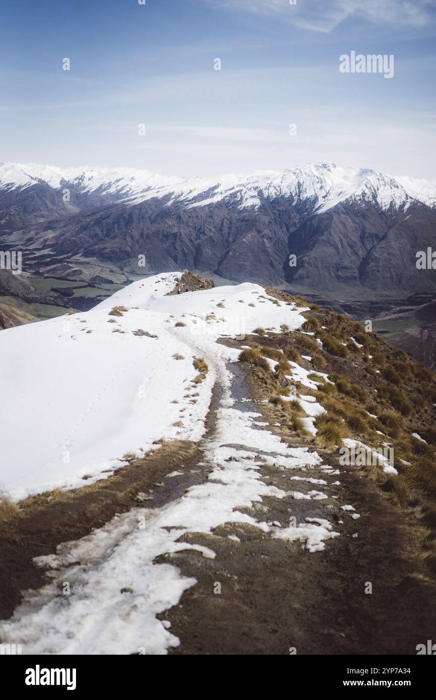 Snowy hiking trail leads through the mountain landscape with blue sky ...