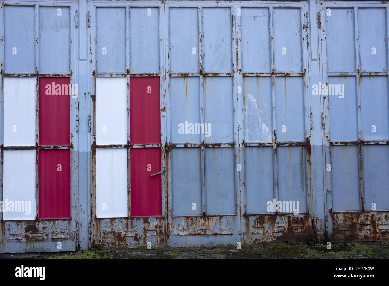 Rusty metal doors with red and white panels on an industrial building ...