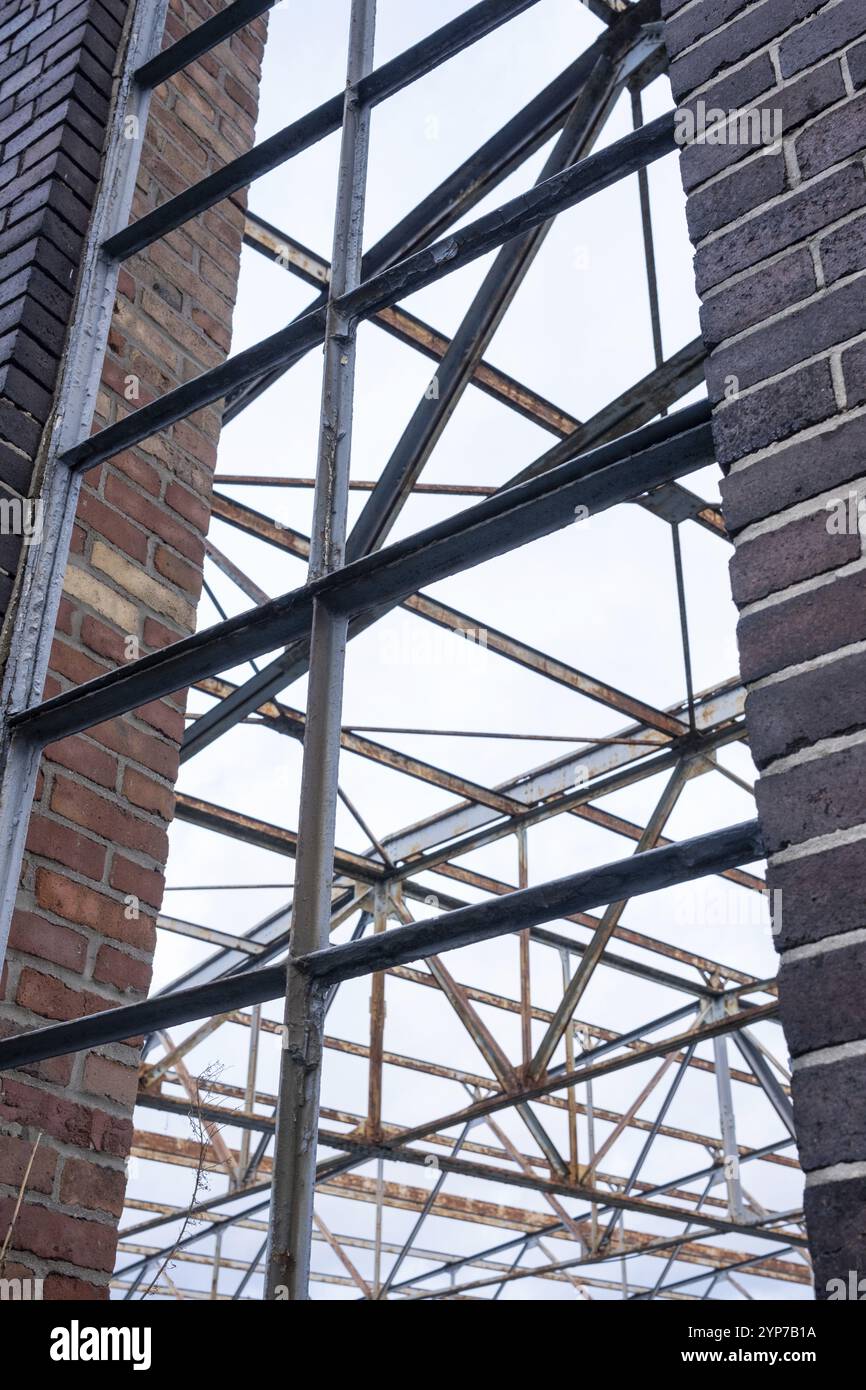 Industrial metal framework within partial brick walls against a cloudy ...