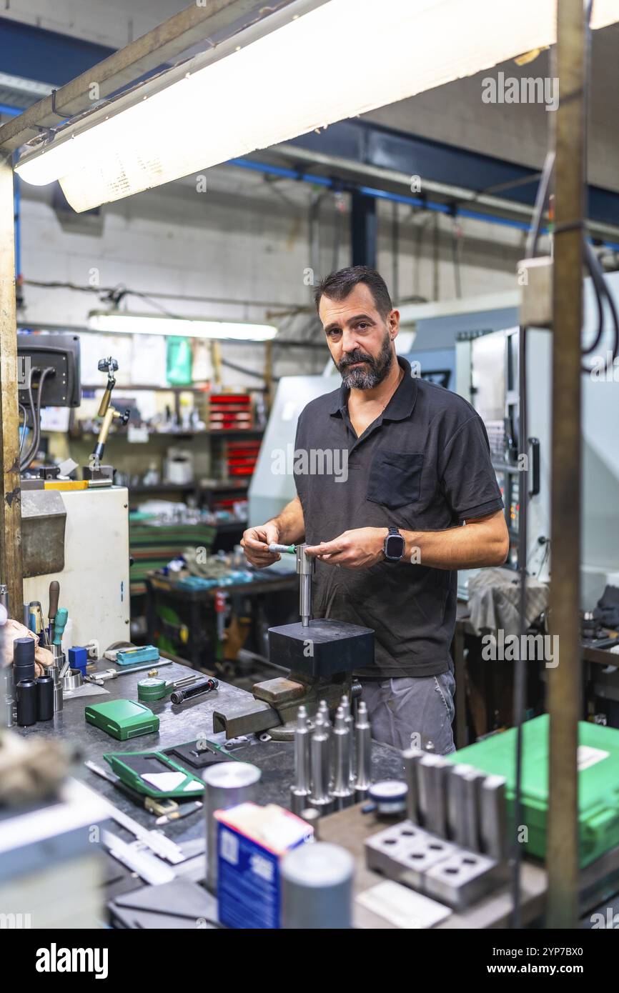 Vertical photo of a serious male caucasian worker using micrometer ...