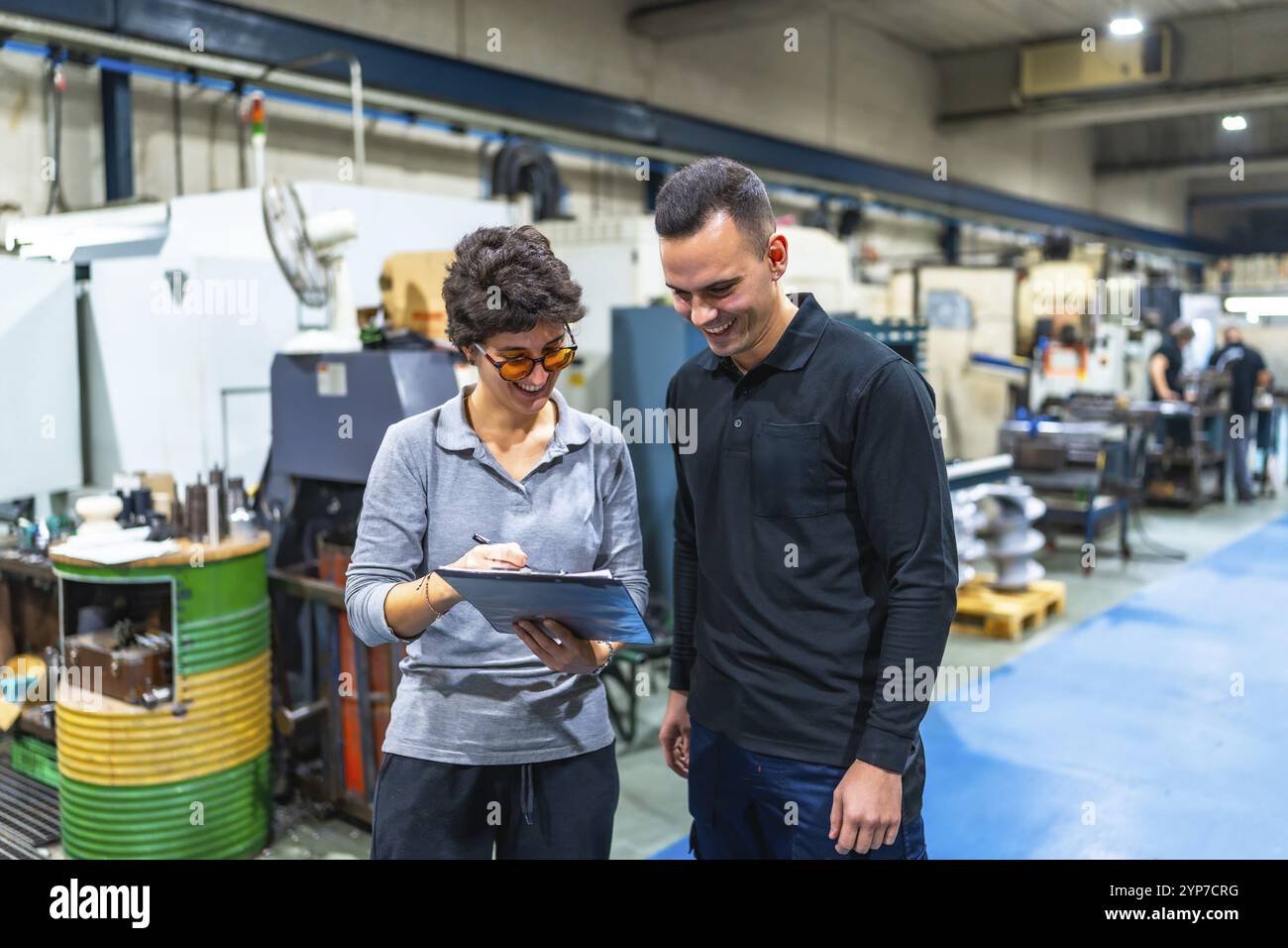 Businesswoman with male caucasian worker talking and inspecting a cnc ...