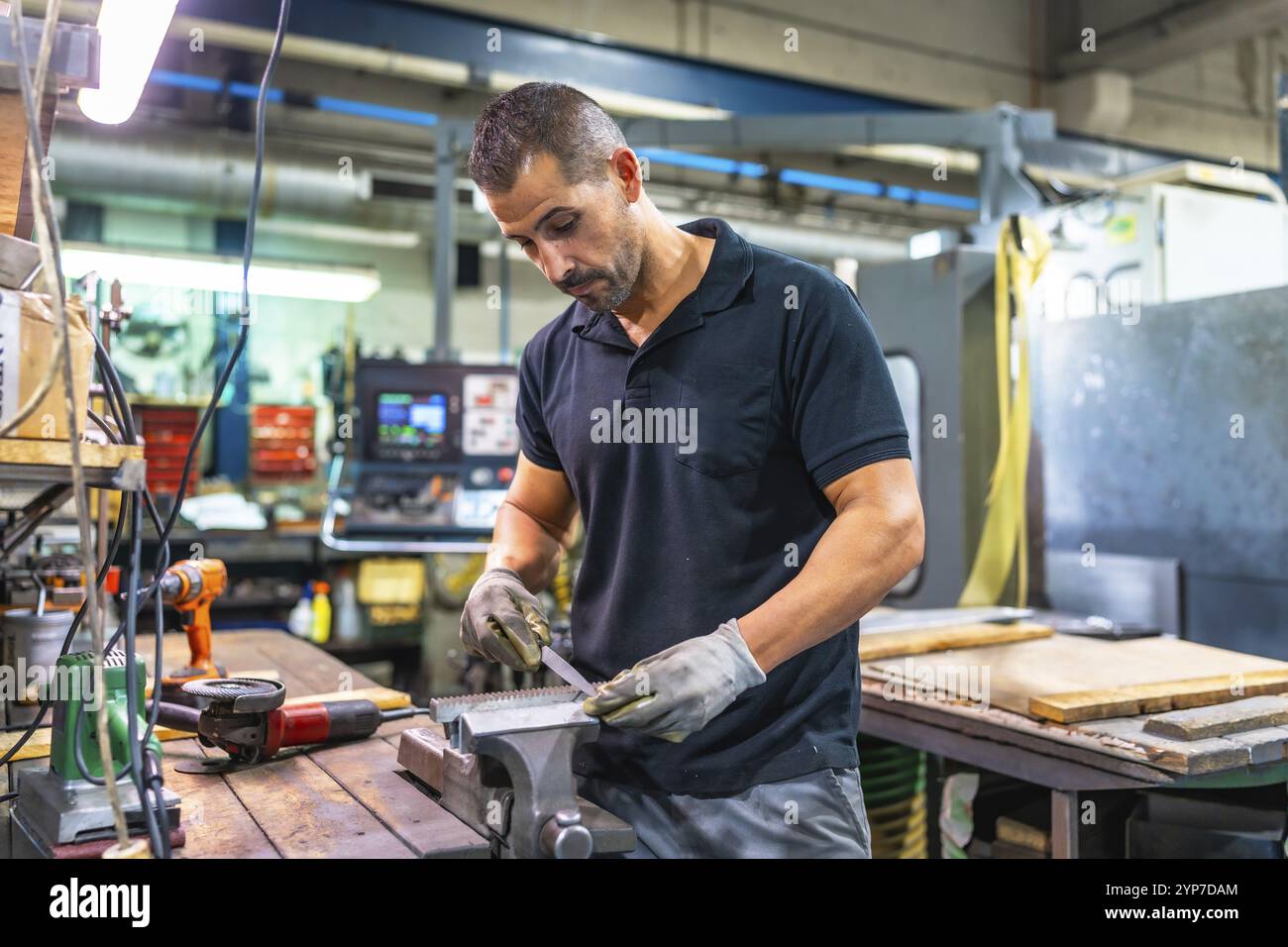 Caucasian adult male manual worker working in metal factory using drill ...