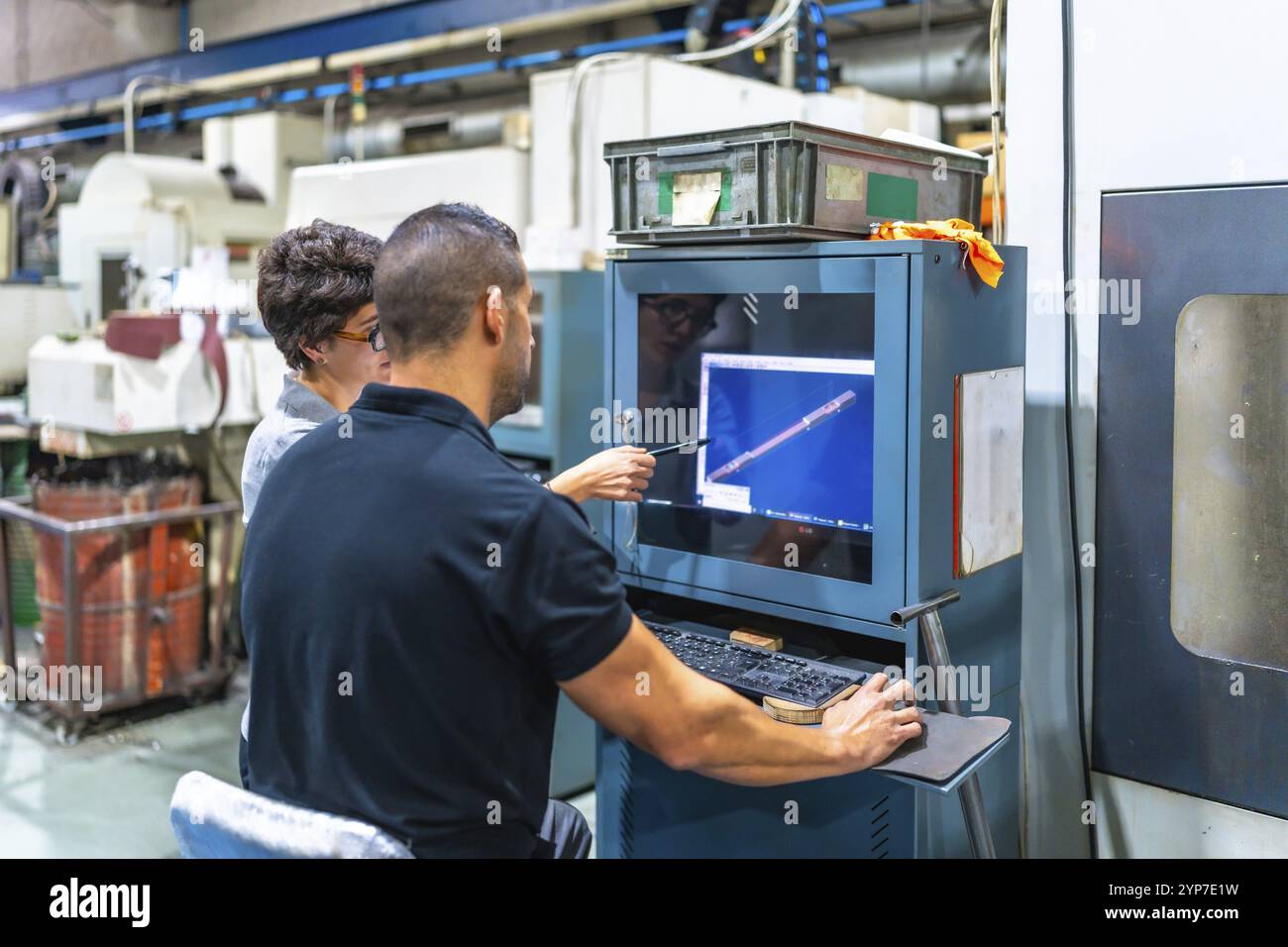 Rear view of a female manager and engineer using computer in a cnc ...
