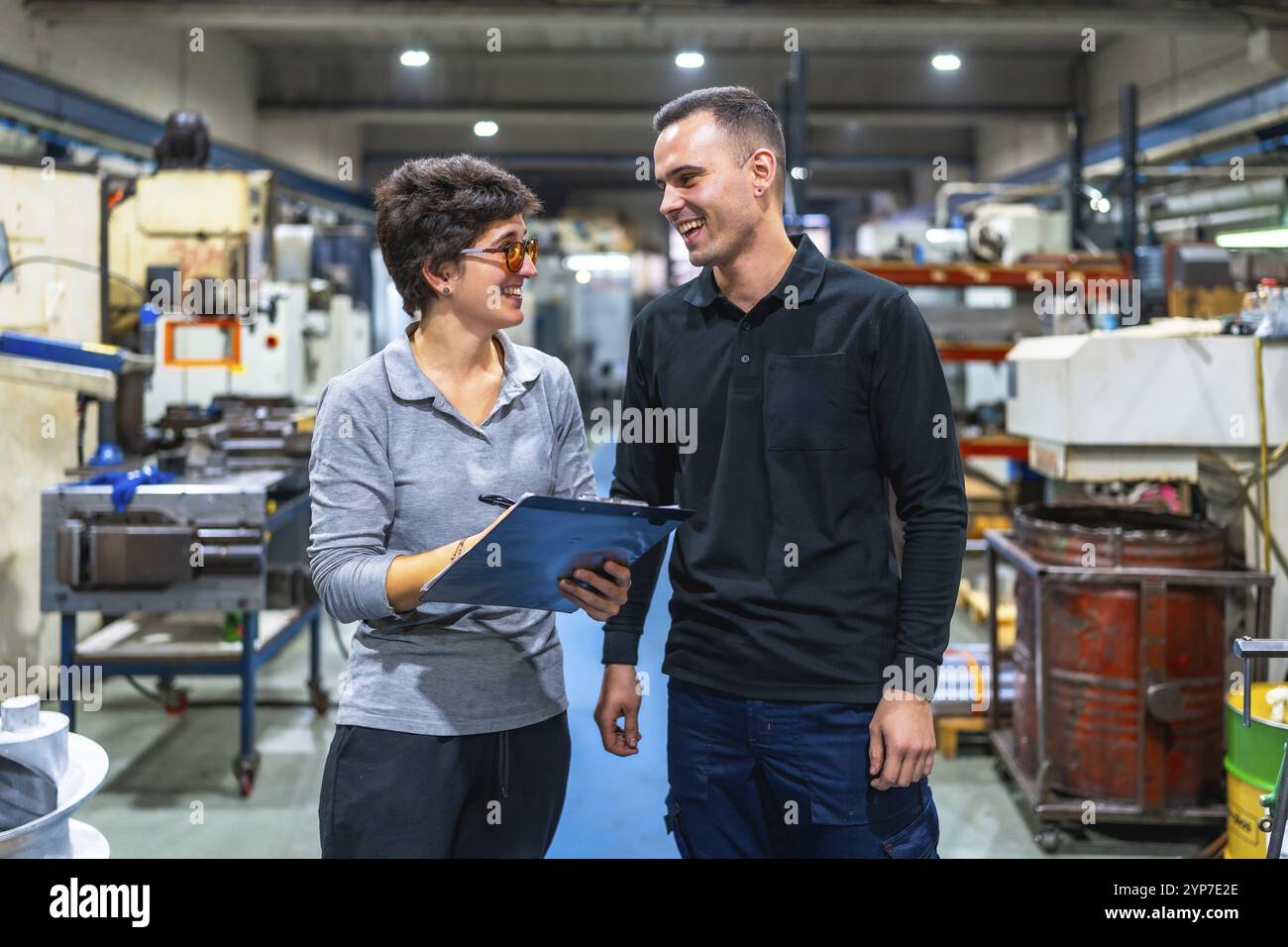 Female boss and worker talking happily and animatedly in a cnc factory ...