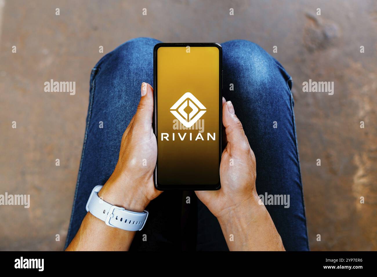 In this photo illustration, the Rivian logo is displayed on a ...