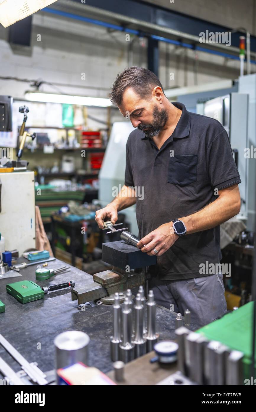 Vertical photo of an adult caucasian male worker using micrometer to ...