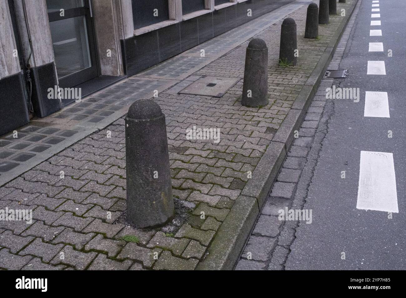 Stone bollards line an urban sidewalk adjacent to a building Stock Photo - Alamy