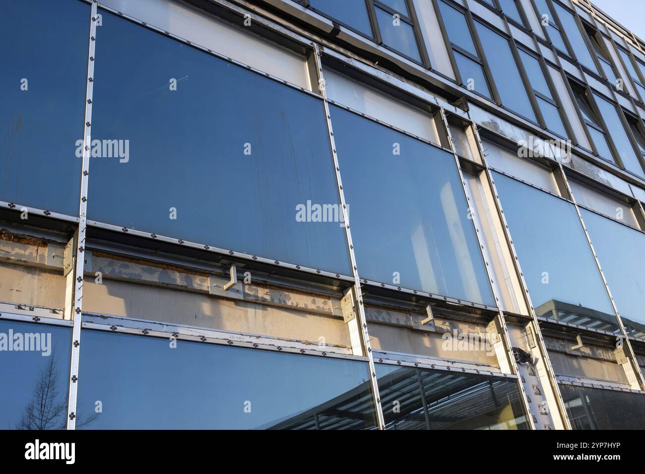Modern glass building reflecting blue sky and surrounding structures ...