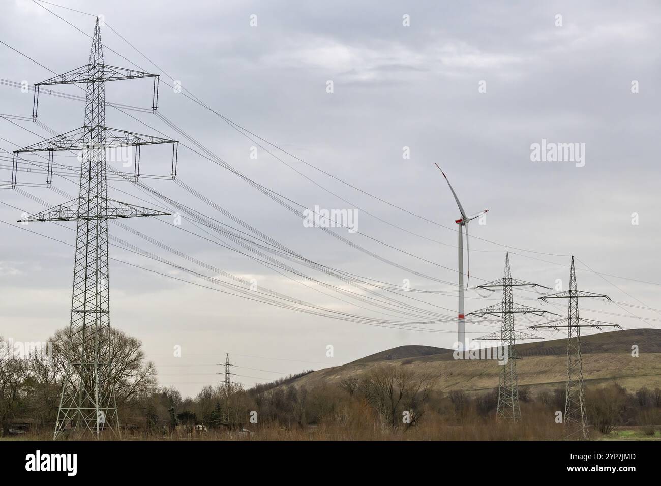 High-voltage pylons with wind turbine in german industrial landscape ...