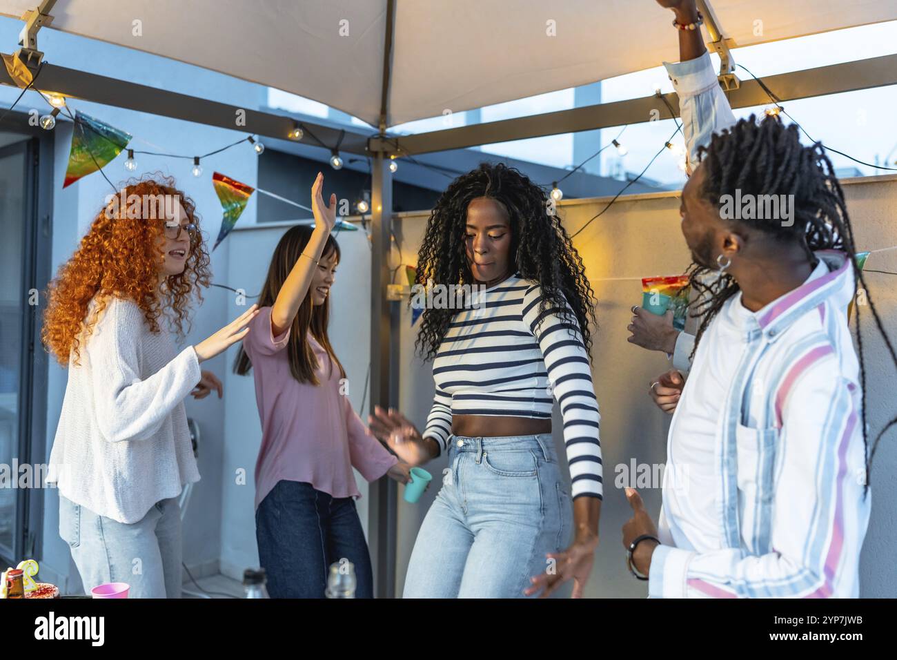 African woman dancing while multi-ethnic friends circle her in a ...