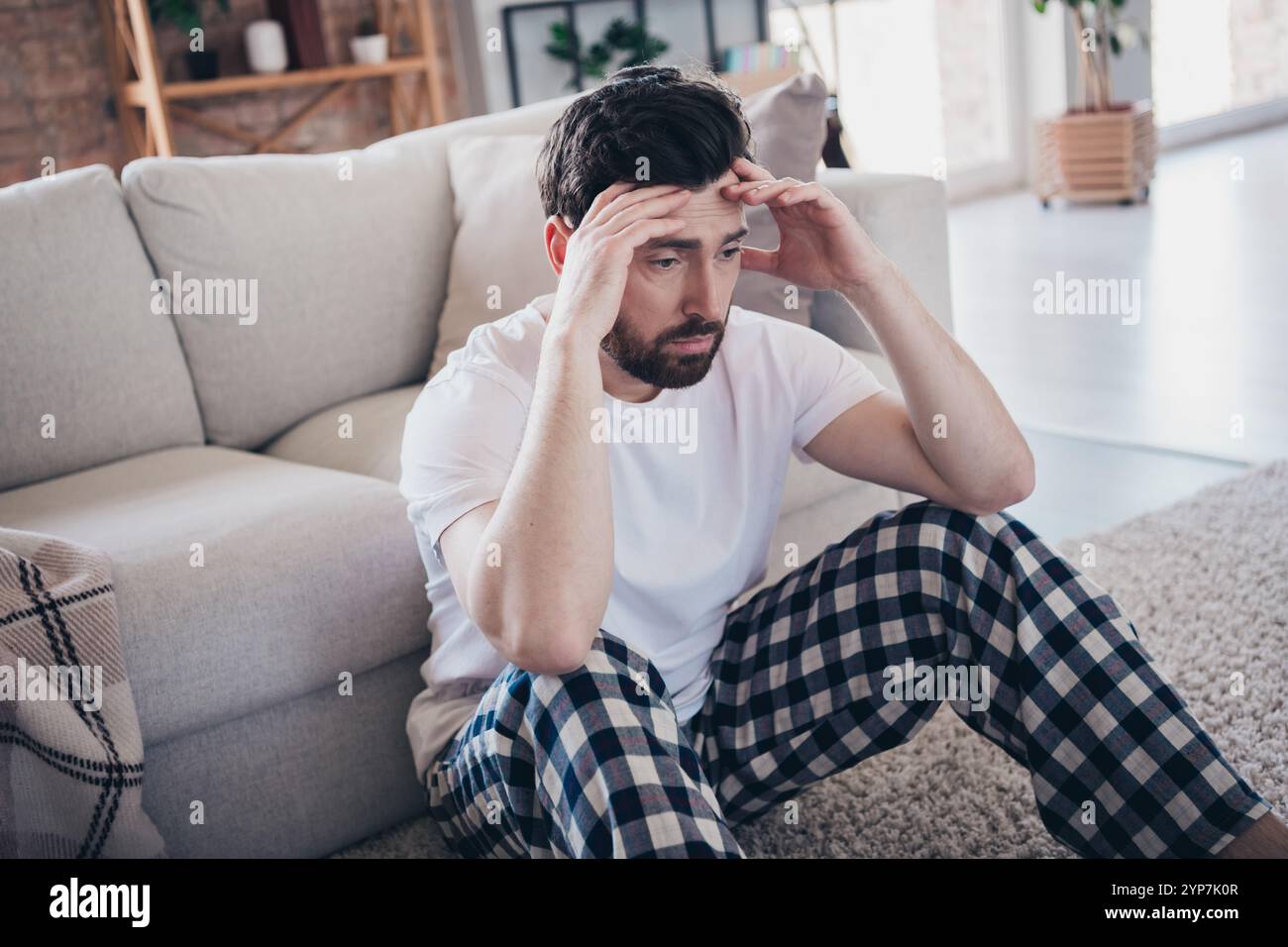 Photo of thoughtful sad upset man wearing pajama sitting on floor ...