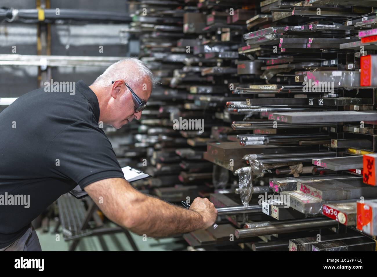 Mature caucasian male inspector doing inventory and measuring metal ...